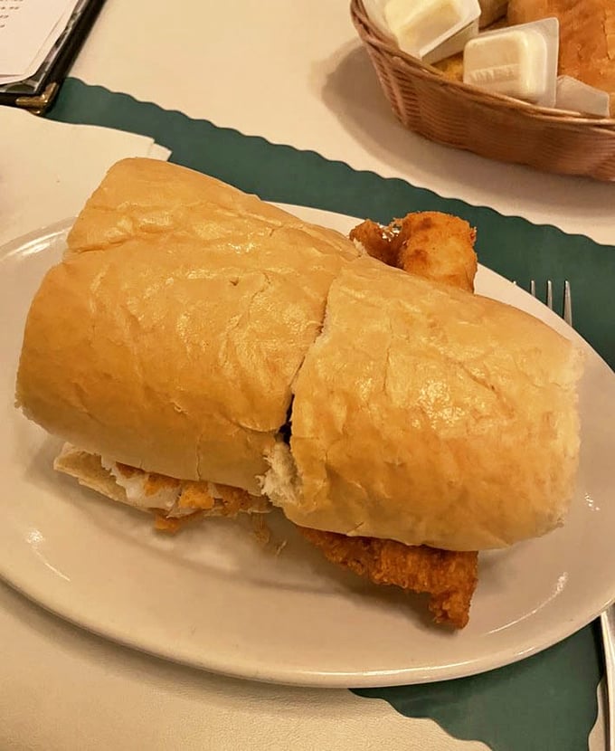 The fish sandwich arrives like a golden treasure on a Mancini roll—crispy, substantial, and demanding both hands and your full attention.
