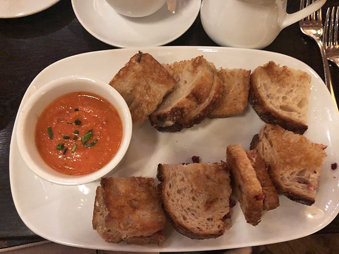 Grilled cheese elevated to art form—crusty artisanal bread flanking melted cheese with tomato soup for dipping. Childhood comfort meets grown-up sophistication.
