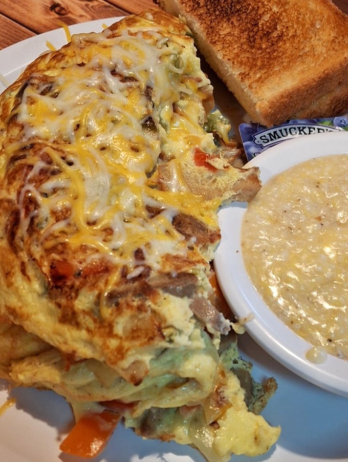 This omelet has more layers than your favorite Netflix drama. Melted cheese cascades over perfectly cooked eggs while grits stand by, ready for their supporting role.