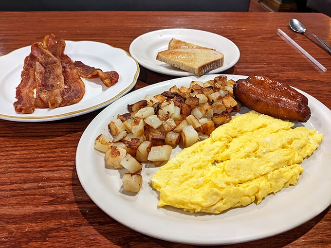 Breakfast alchemy at its finest—fluffy scrambled eggs, golden home fries, and sausage links that snap with that satisfying first bite.