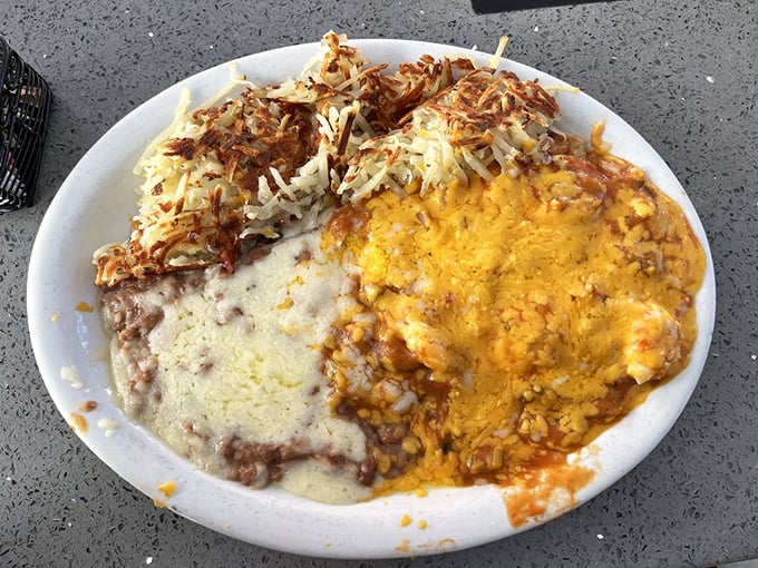 This mountain of cheesy, saucy goodness is what breakfast dreams are made of—hash browns on one side, melted cheddar blanketing the other.