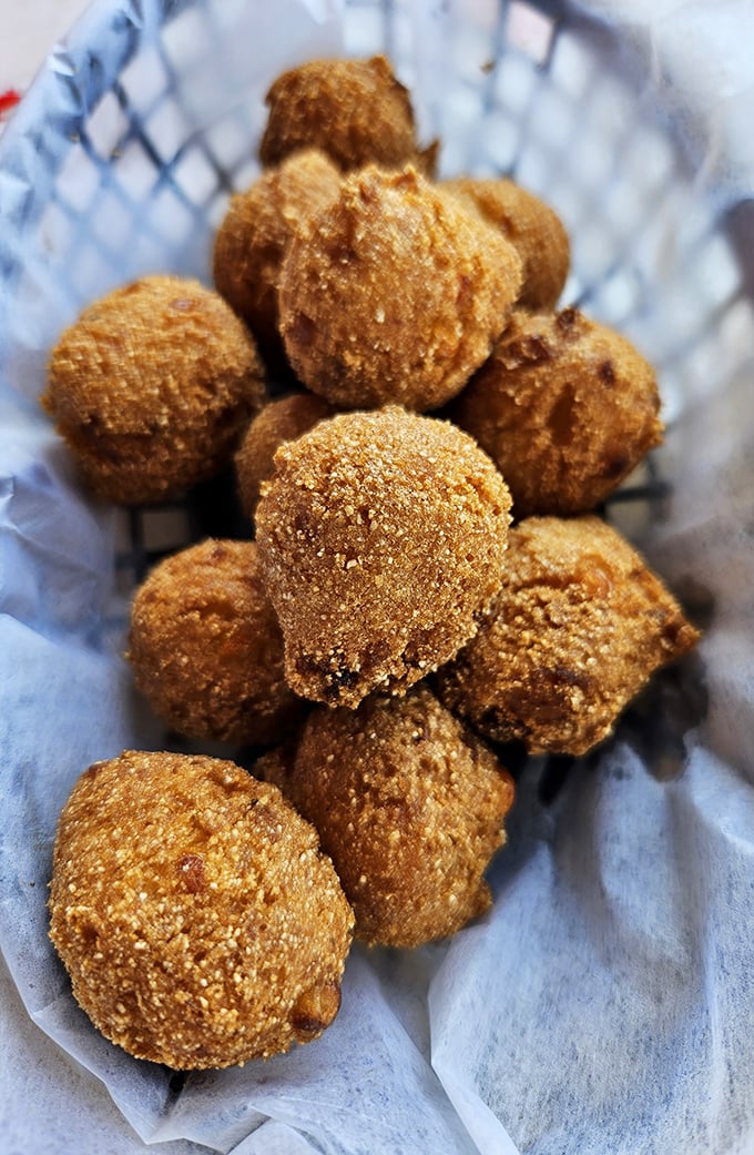 Golden-brown hush puppies huddle together in their basket, waiting to be dipped in honey butter—the perfect sweet counterpoint to all that savory seafood.