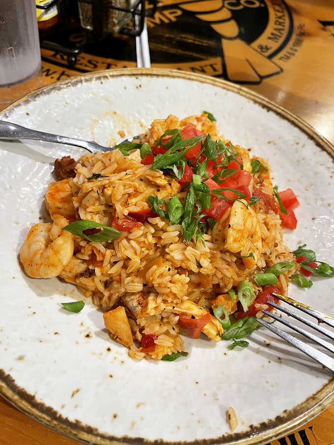 Jambalaya that tells a story with every bite—spicy rice mingling with shrimp and vegetables, topped with fresh scallions and diced tomatoes.