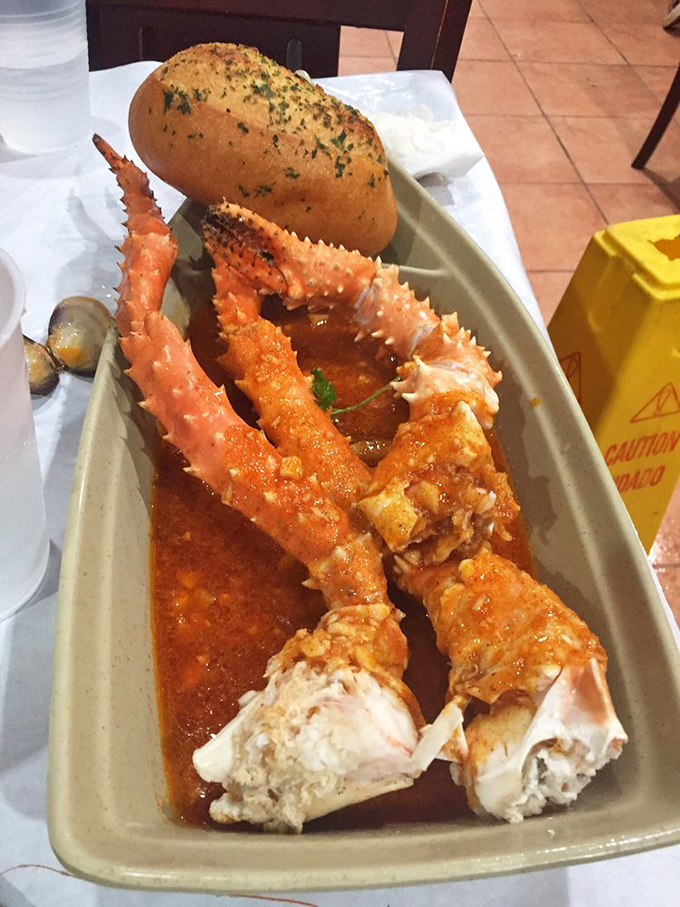 King crab legs bathed in spicy sauce with a side of garlic bread – proof that sometimes the messiest meals create the most pristine memories.