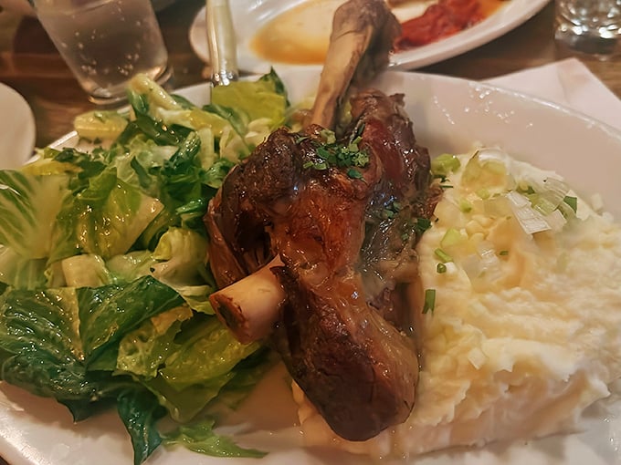 This isn't just any lamb shank – it's a masterclass in slow-cooking, where meat surrenders completely from the bone alongside creamy mashed potatoes.