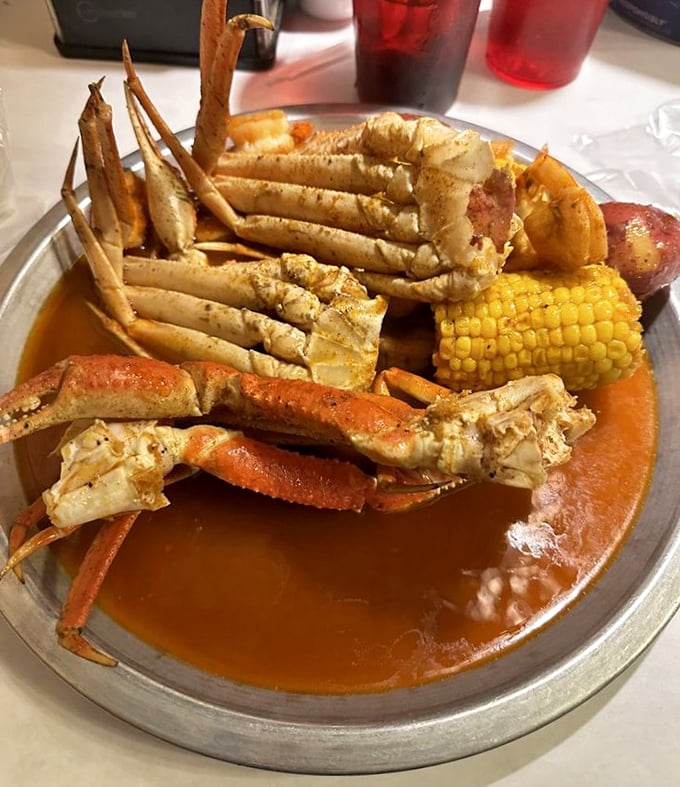Snow crab legs, corn, and potatoes swimming in seasoned sauce – a metal tray treasure chest that rewards those willing to work for their dinner.