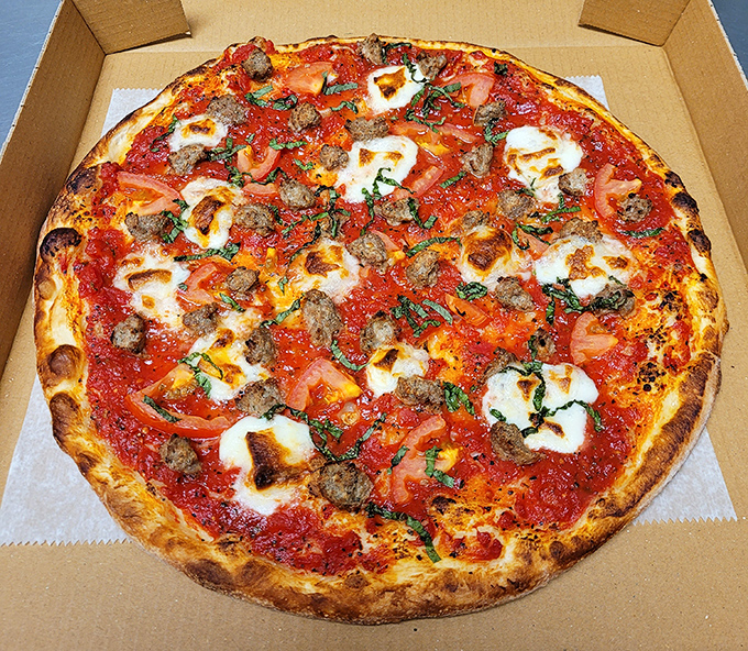 This isn't just pizza—it's a masterpiece of melted cheese, sausage, and fresh tomatoes that would make an Italian grandmother weep with joy.