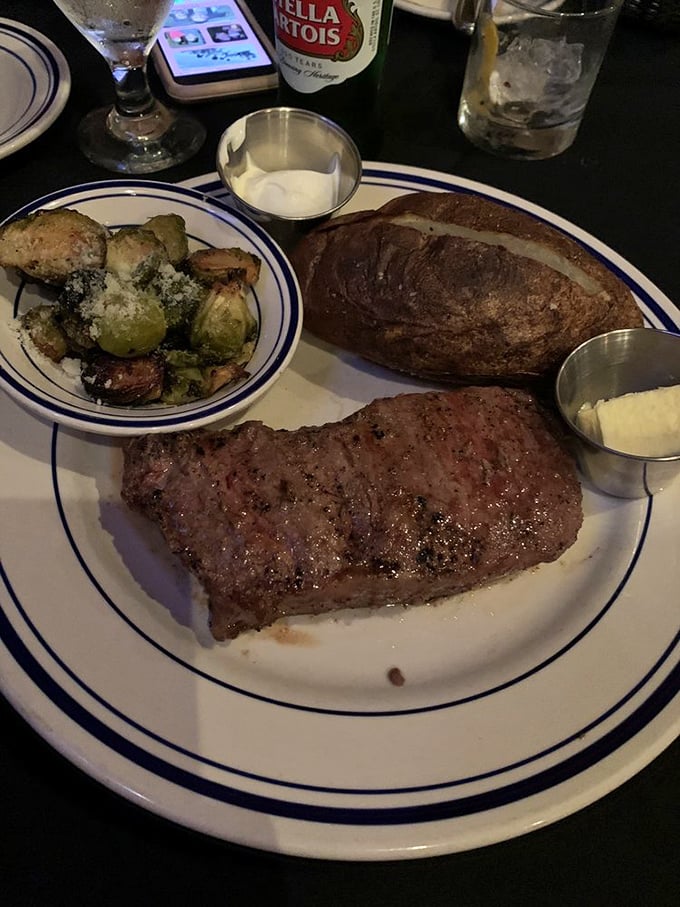 This New York strip isn't just a steak; it's a statement. Paired with Brussels sprouts and a baked potato, it's the holy trinity of steakhouse perfection.