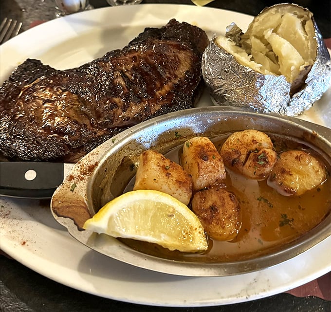 A perfectly seared New York Strip flanked by a loaded baked potato and scallops—proof that sometimes the classics never need reinvention.