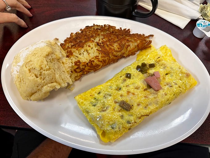 The holy trinity of breakfast: a perfectly folded omelet, crispy hash browns, and a biscuit that would make any Southern grandmother nod in approval.
