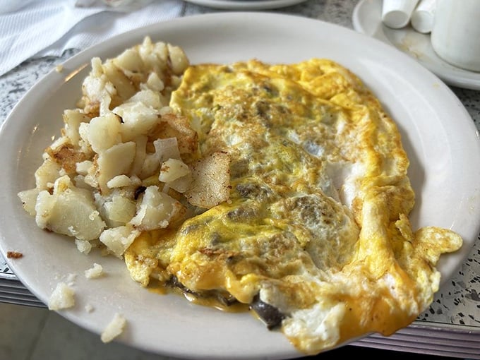 This isn't just an omelet—it's a fluffy yellow blanket of eggs keeping those perfectly seasoned home fries warm and cozy.