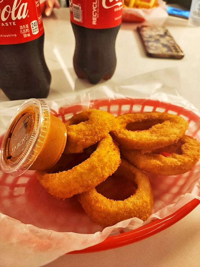 Golden onion rings with a side of dipping sauce—crispy, light, and perfectly engineered for that satisfying crunch that makes neighboring diners jealous.