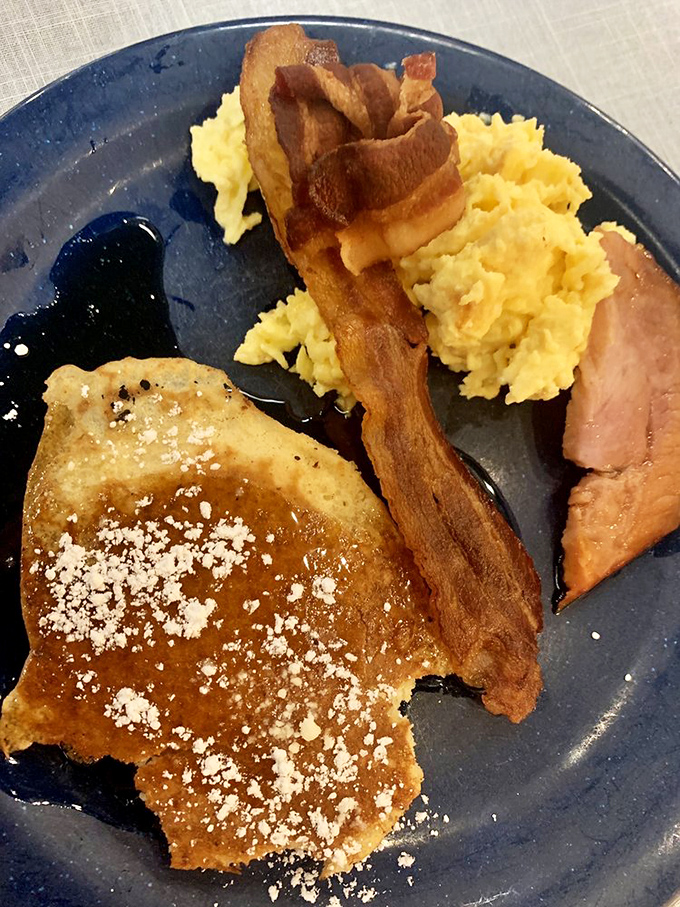 Breakfast of champions: A golden pancake dusted with powdered sugar, crispy bacon standing at attention, and eggs that would make any hen proud.