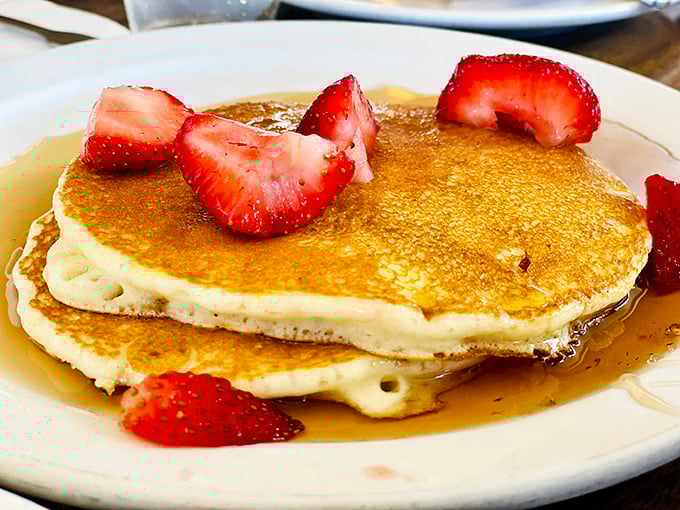 These pancakes aren't just breakfast, they're edible sunshine—golden discs of fluffy perfection crowned with strawberries that make mornings worth facing.