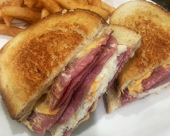 This Reuben sandwich isn't just stacked—it's architected. Layers of corned beef and sauerkraut creating the skyscraper of sandwich dreams.