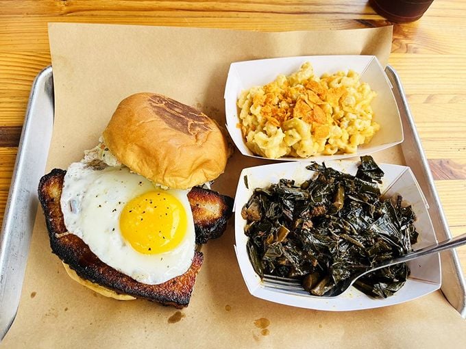 This pork belly sandwich with a sunny-side-up egg isn't just breakfast meeting lunch—it's a flavor summit with mac and cheese and greens as honored delegates. 