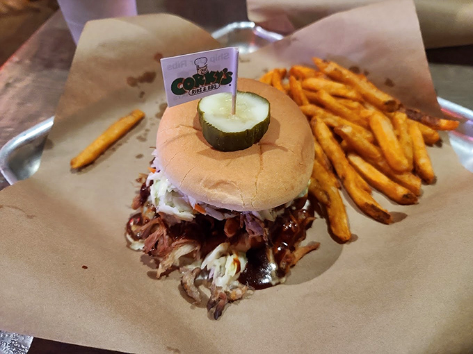 The pulled pork sandwich—a masterpiece of smoke and patience topped with slaw and crowned with a pickle flag. Victory never tasted so good.