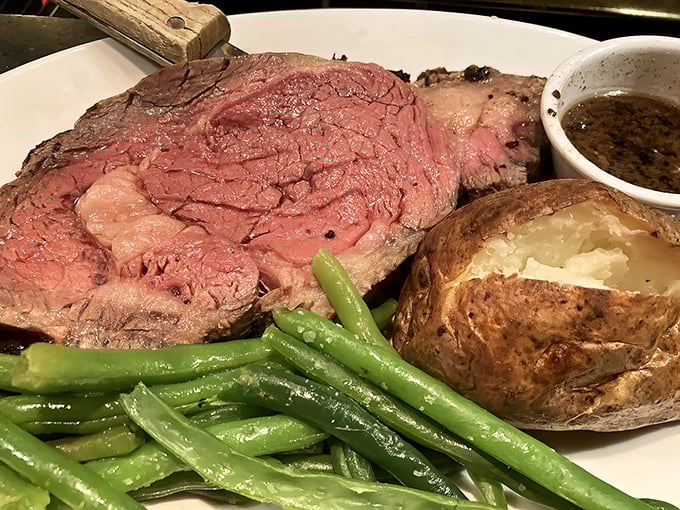 The prime rib arrives like royalty on a white throne—perfectly pink, impossibly tender, with a baked potato sidekick worthy of its own fan club.