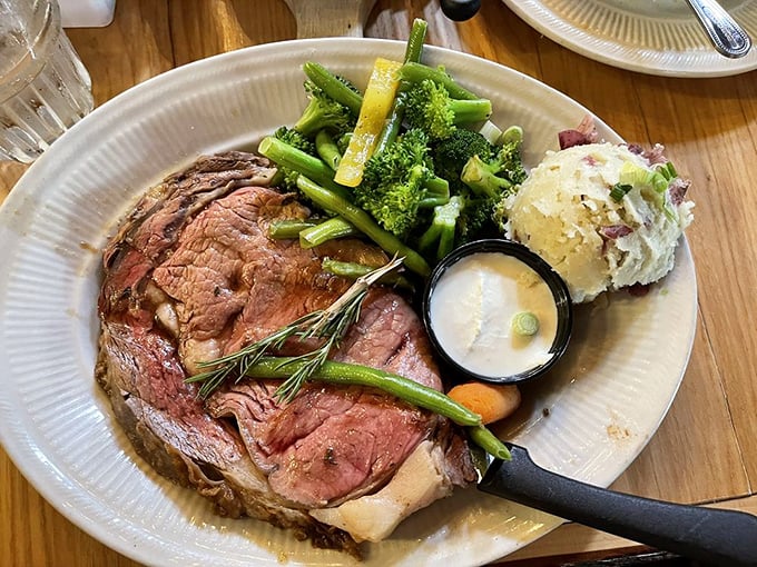 The prime rib arrives like royalty—perfectly pink, herb-crusted, and accompanied by vegetables that know their supporting role.