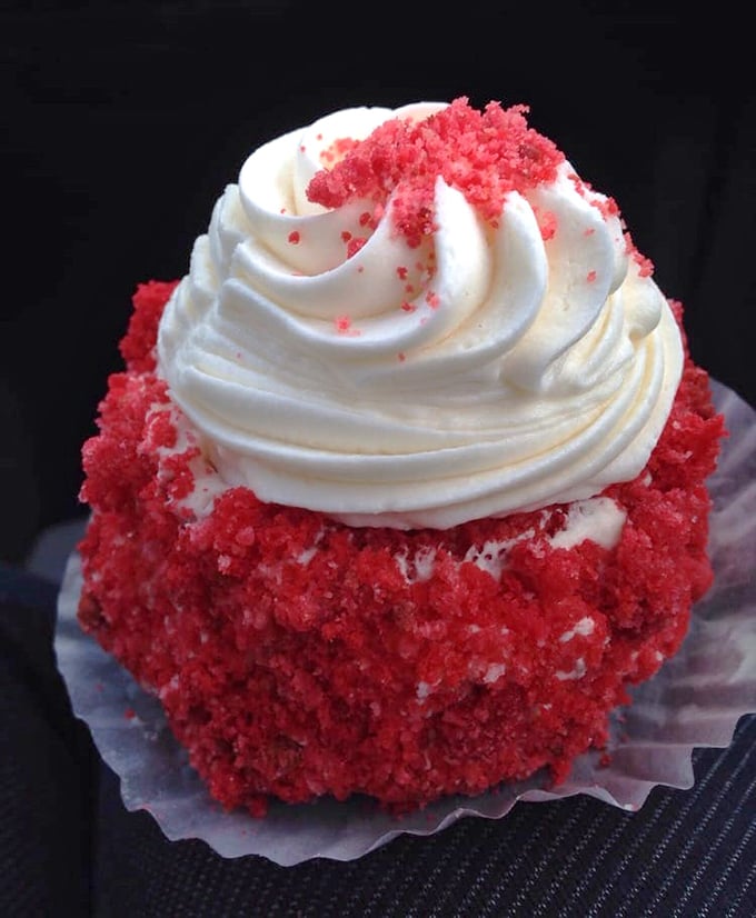 The red velvet cupcake doesn't whisper its presence—it announces itself with a crown of cream cheese frosting fit for bakery royalty.