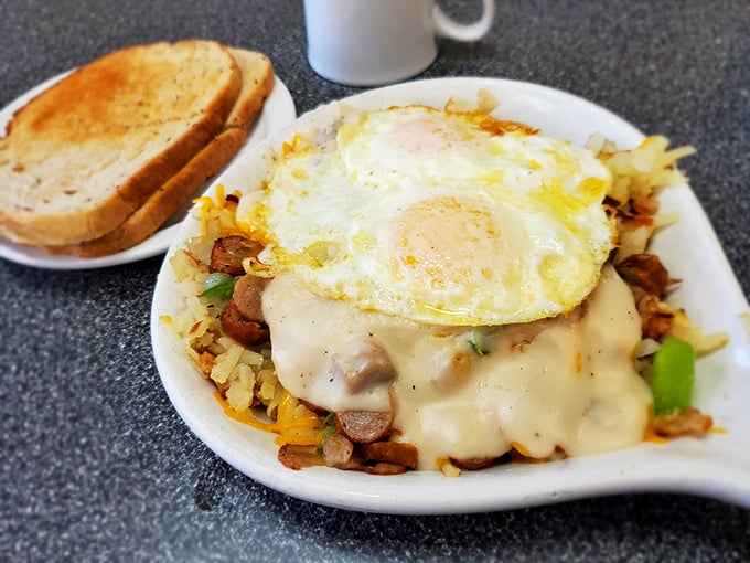 Breakfast alchemy at its finest—potatoes transformed into golden hash browns, crowned with eggs and smothered in cheese that stretches with each forkful.