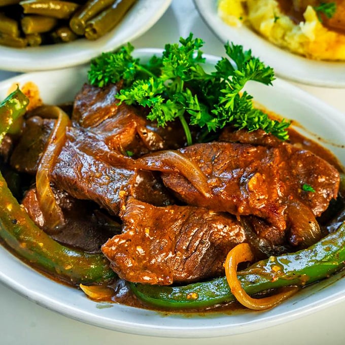 These smothered pork chops aren't just food – they're time travel. One bite and you're sitting in your grandmother's kitchen on a Sunday afternoon.