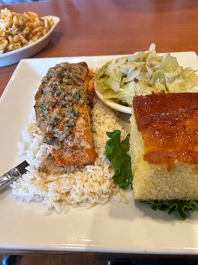 The herb-crusted salmon doesn't just sit on the rice—it presides over it like royalty, with cabbage and cornbread as loyal subjects.
