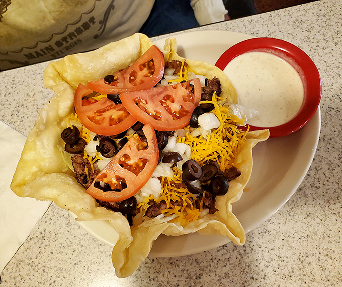 This taco salad bowl isn't just food—it's architecture. The crispy shell cradles a mountain of ingredients with a side of ranch that's practically begging for a dip.