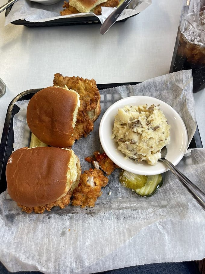 The Indiana state sandwich in all its glory—a breaded tenderloin that refuses to acknowledge the boundaries of its bun, paired with fries that could make a Frenchman weep.