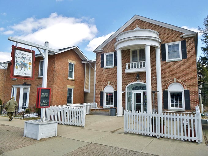 The Village Inn's colonial-inspired architecture houses comfort food that fuels both body and conversation. That white picket fence isn't just for show—it's containing culinary happiness.
