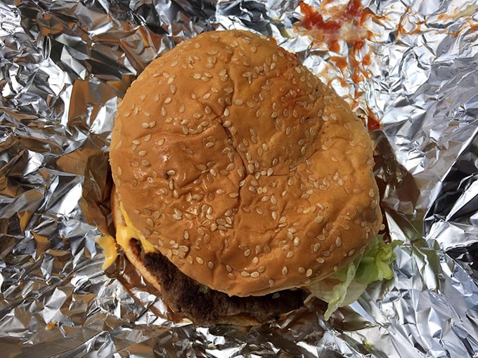 The sesame-studded bun barely contains what lies beneath – a burger that demands respect and possibly an extra napkin or three.