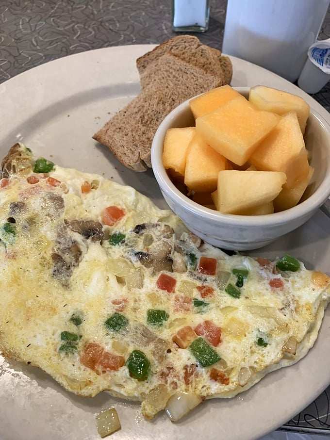 This veggie omelet doesn't apologize for being healthy—it's too busy showing off its colorful peppers and mushrooms alongside fresh cantaloupe.