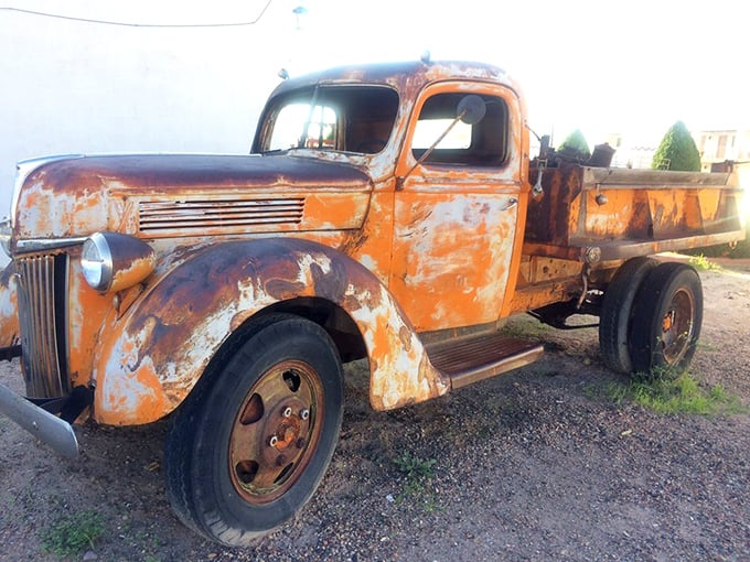 This weathered orange truck hasn't hauled anything in decades except dreams and photo opportunities for nostalgic travelers.