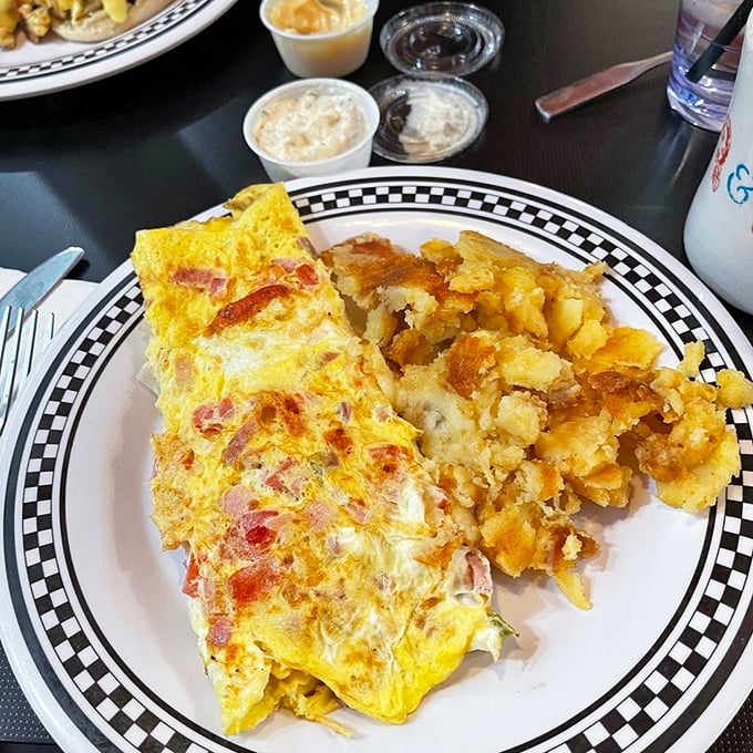 This Western omelet and home fries combo isn't just breakfast—it's edible sunshine on a classic black-and-white checkered plate, the way diners have served it for generations.