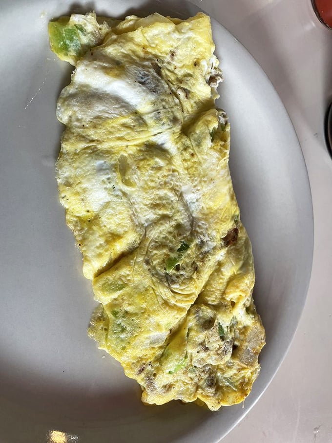 Behold the Western omelet in its natural habitat—a fluffy yellow landscape where peppers and ham live in perfect harmony.