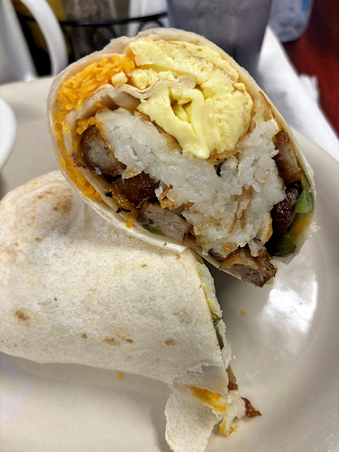 Breakfast burrito brilliance—where hashbrowns, eggs, cheese, and sausage unite in tortilla-wrapped harmony. The cross-section reveals the architectural genius behind this handheld masterpiece.