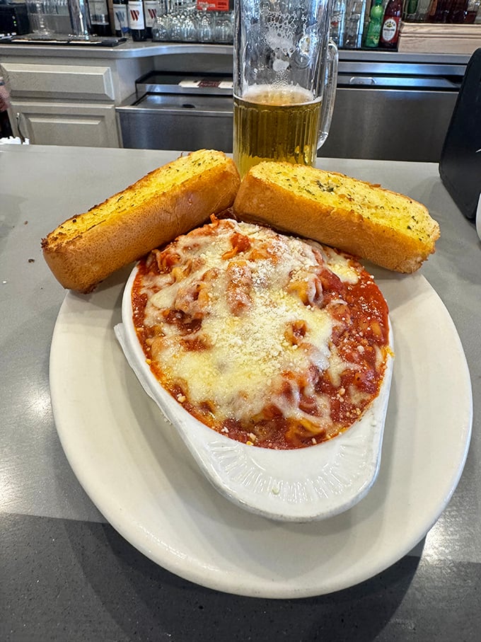 Garlic bread standing at attention beside a bubbling cavatini—like comfort food bodyguards protecting a treasure of cheese and sauce.