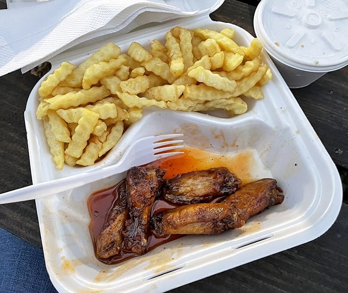 Golden chicken wings swimming in sauce with a mountain of crispy fries for good measure.