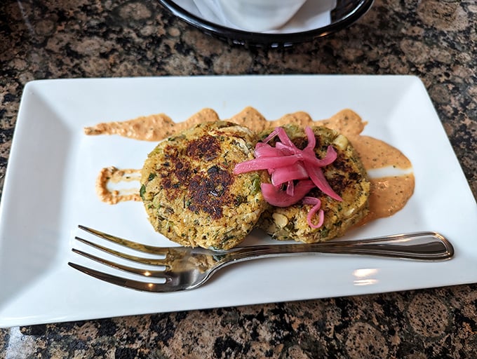These crab cakes—more crab than cake—are served with pickled red onions that cut through the richness like a perfectly timed punchline.