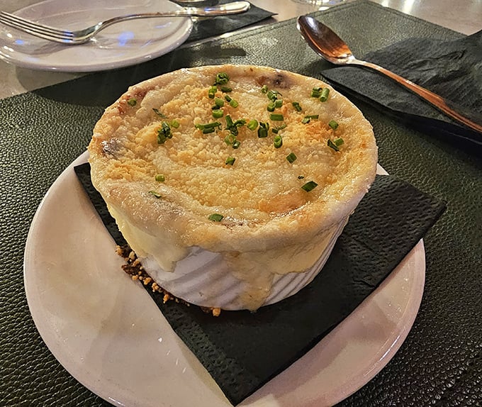 The legendary French onion soup, crowned with a golden dome of melted cheese that stretches dramatically with each spoonful – worth the trip alone.