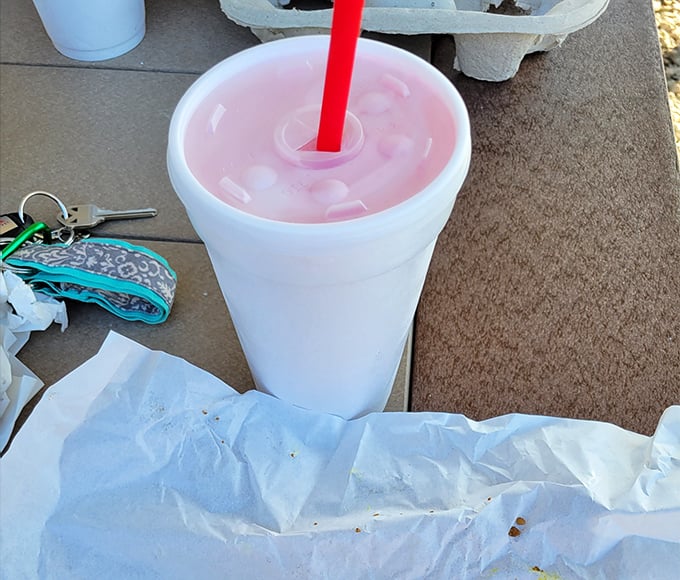 A strawberry milkshake so thick the straw stands at attention—summer in a styrofoam cup, pink as a Midwest sunset.