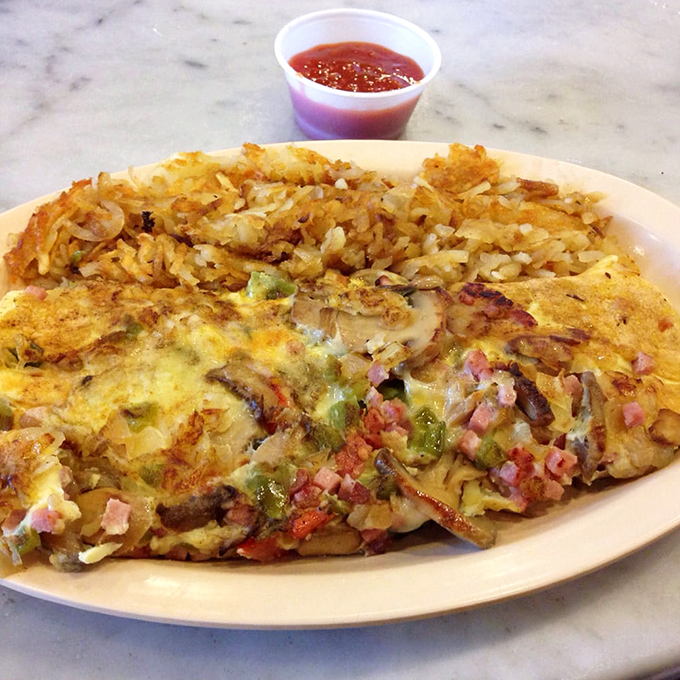 Omelets here aren't just folded eggs; they're fluffy yellow canvases painted with ham, peppers, and cheese, with crispy hash browns as the perfect frame.