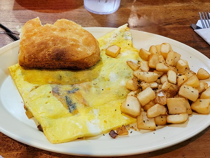Breakfast perfection: a fluffy omelet that's seen the right amount of griddle time, paired with crispy home fries and a biscuit that means business.