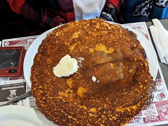 The pancake that launched a thousand road trips. Golden-brown, plate-sized, and sporting a perfect butter crown – breakfast royalty.
