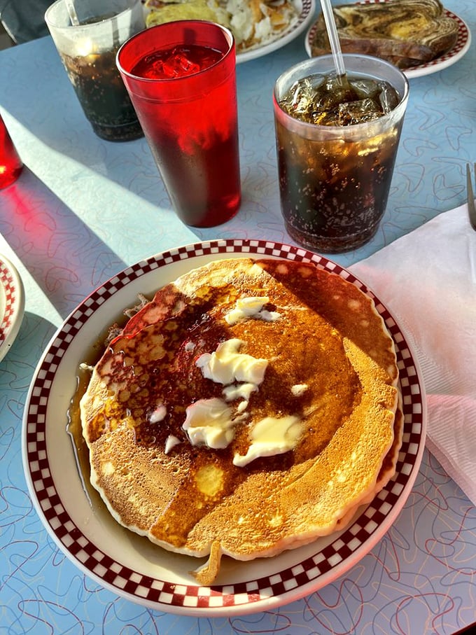 This pancake isn't just large—it's the size of a small frisbee. Butter melting into those perfect golden divots is breakfast poetry in motion.