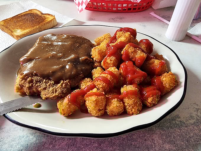 Country fried steak smothered in gravy alongside crispy tater tots—a plate that doesn't just feed your hunger but somehow nourishes your soul too.