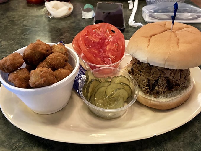 Hush puppies standing guard beside a pulled pork sandwich that's practically bursting at the seams—this is what barbecue dreams are made of.