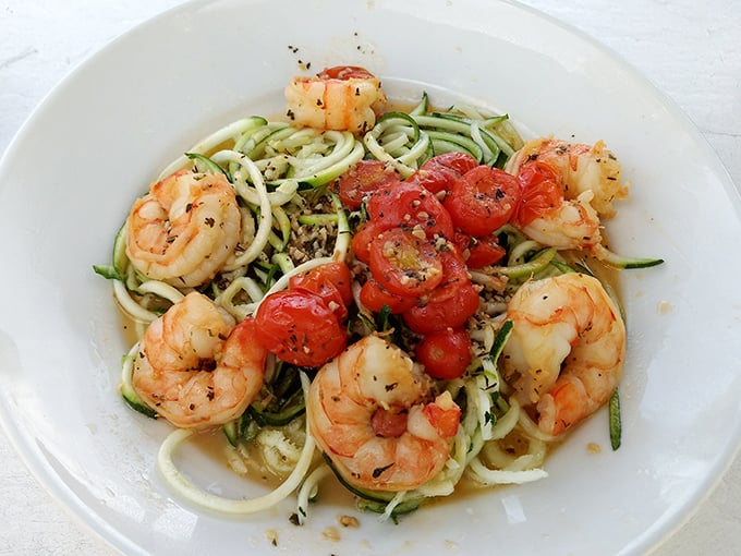 Plump shrimp dance around spiralized zucchini "pasta" with burst tomatoes—proof that healthy eating and vacation indulgence can coexist beautifully.
