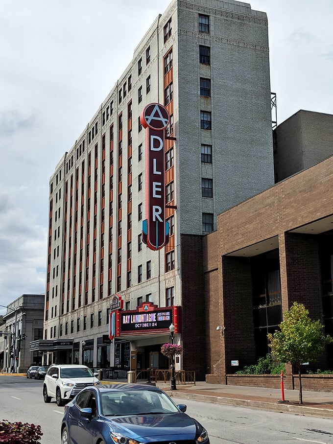Downtown Davenport shines with local charm as cars pass the historic Adler Theatre, a beloved landmark filled with culture and creativity.