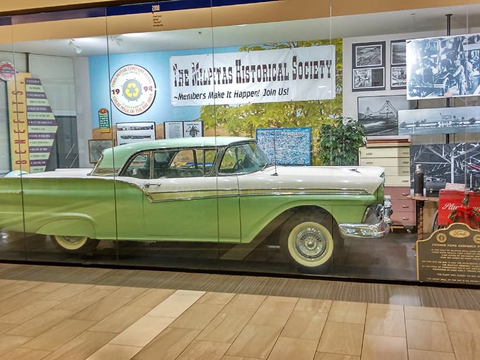 A vintage Ford Fairlane sits majestically behind glass, nodding to the mall's automotive past—from assembly lines to shopping lines.